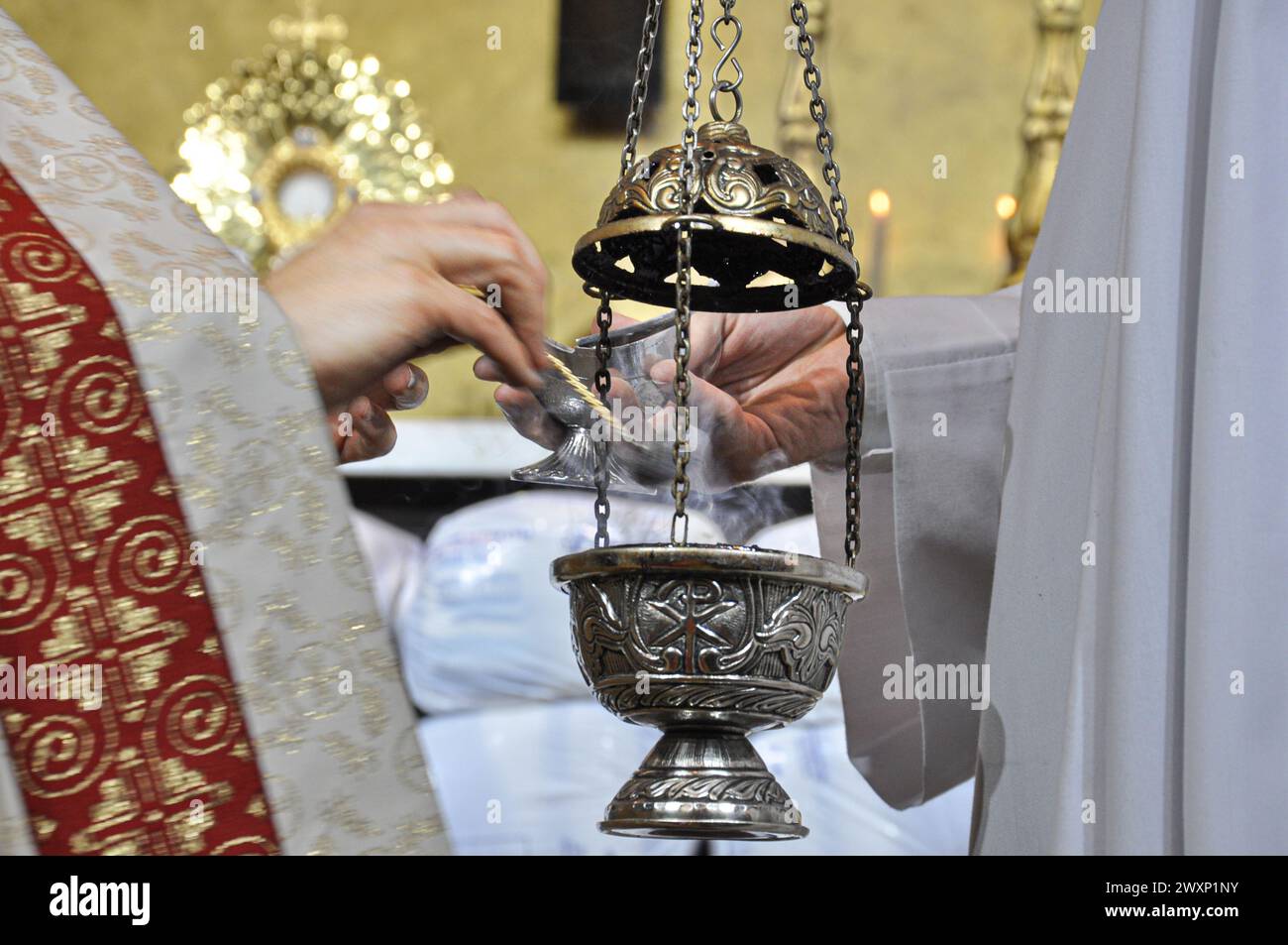 The priest takes insense from the vessel and places it in the thurible ...