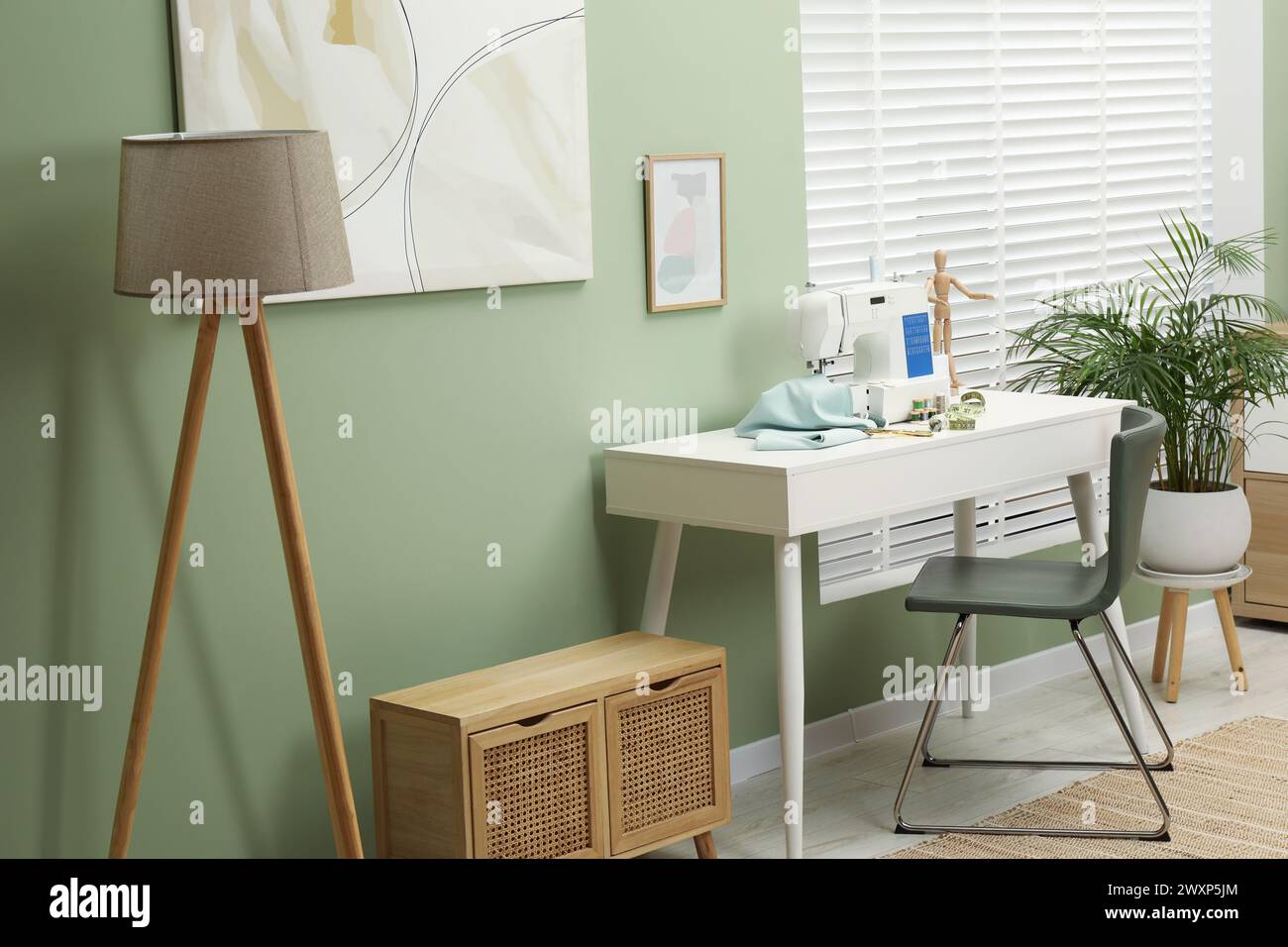Modern sewing machine with cloth and craft accessories on white table ...