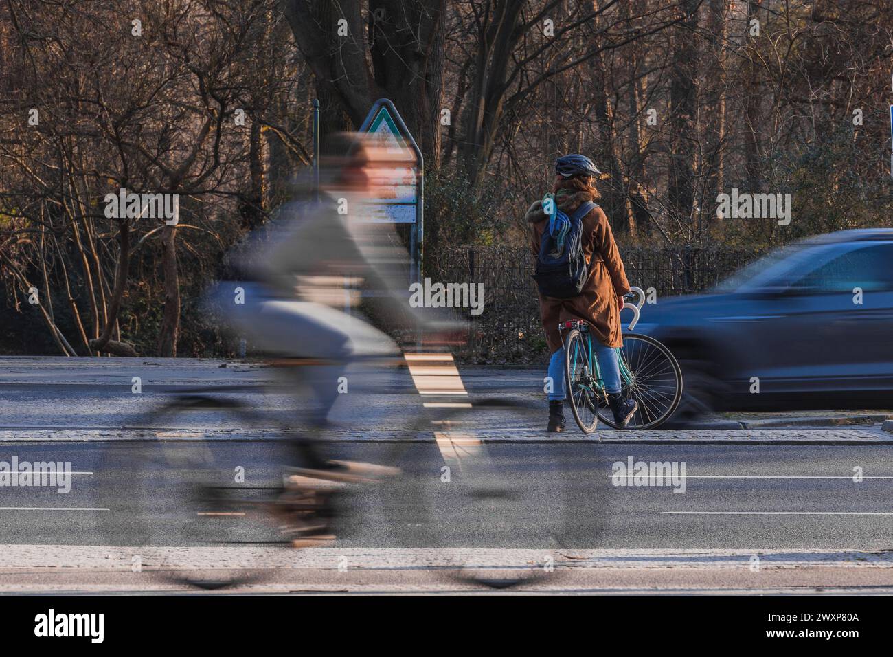 Female cyclist is waiting to cross the road, while standing on the ...