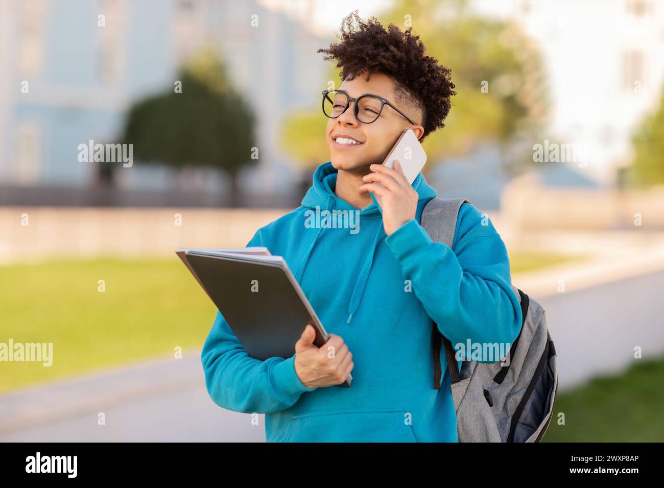 Student talking on phone with textbook in hand Stock Photo - Alamy