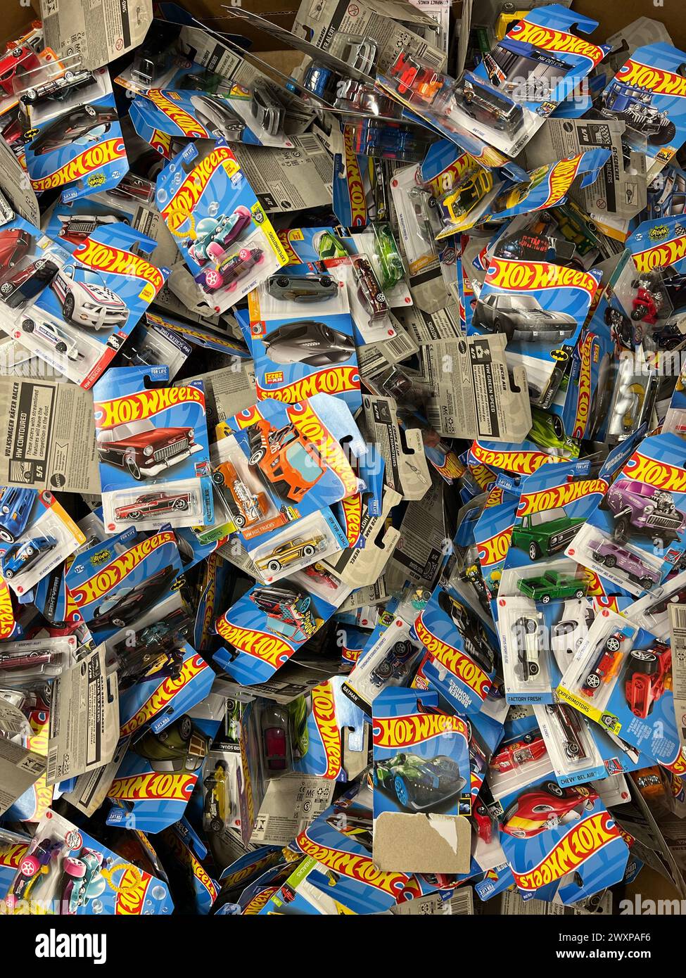 A collection of Hot Wheels toy cars neatly stacked in a cardboard box ...
