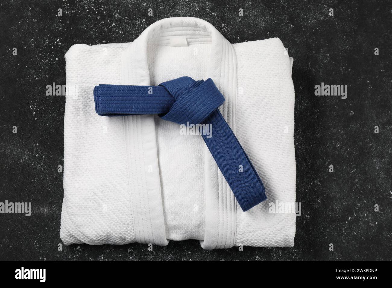 Blue karate belt and white kimono on gray textured background, top view ...