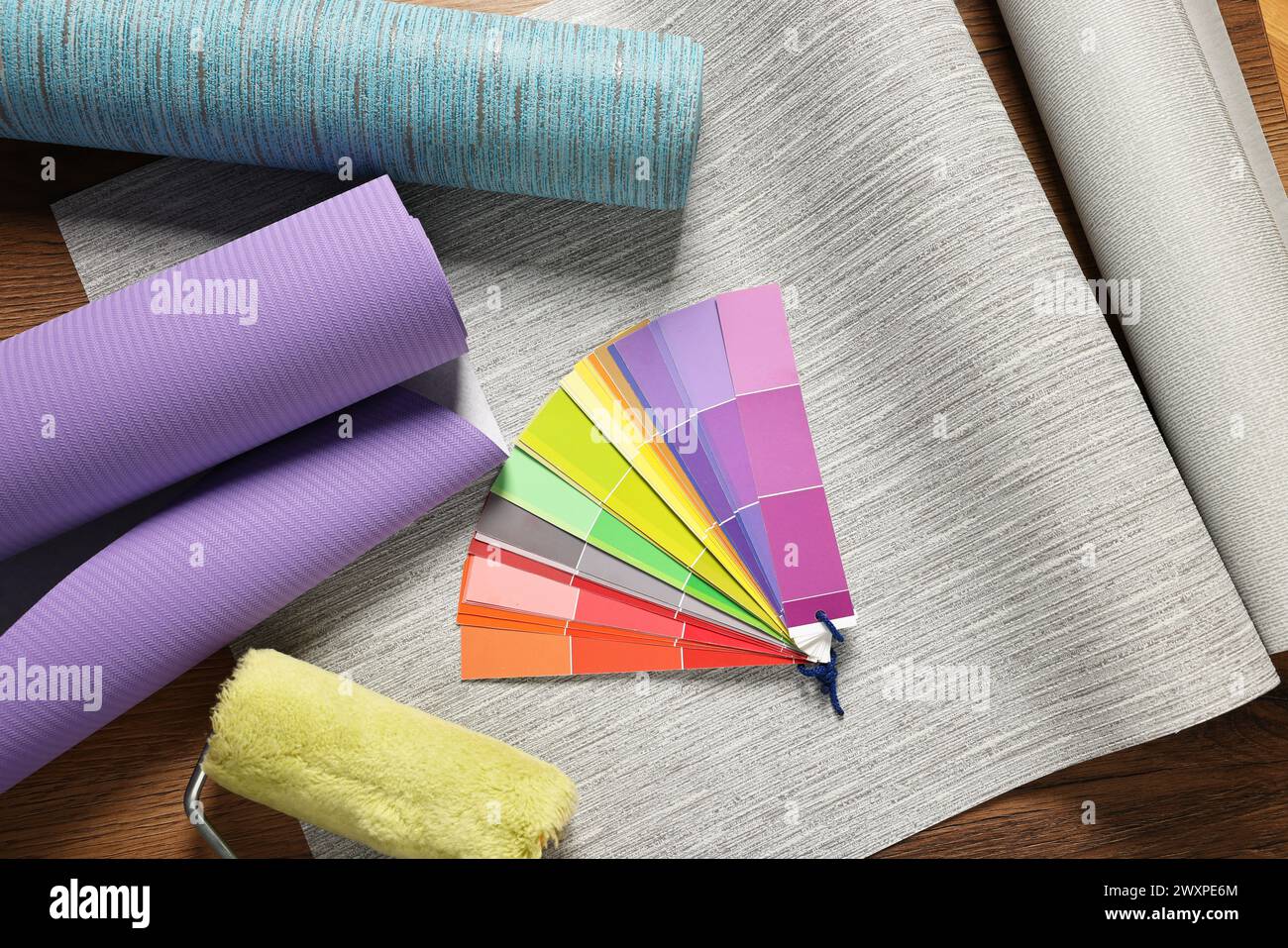 Different wallpaper rolls, roller and color palette samples on wooden ...