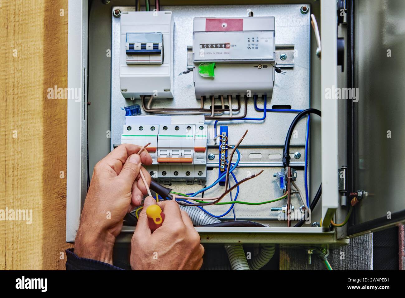 Outdoor switchboard on wall of country house, an electrician connects ...
