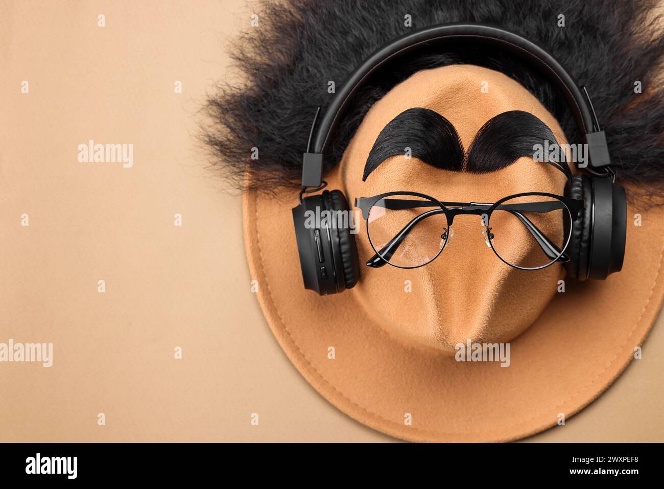 Man's face made of artificial hair, eyebrows, glasses and hat on beige ...