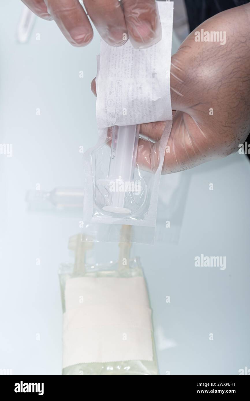 Nurse with protective glove, opening syringe packaging vertical Stock ...