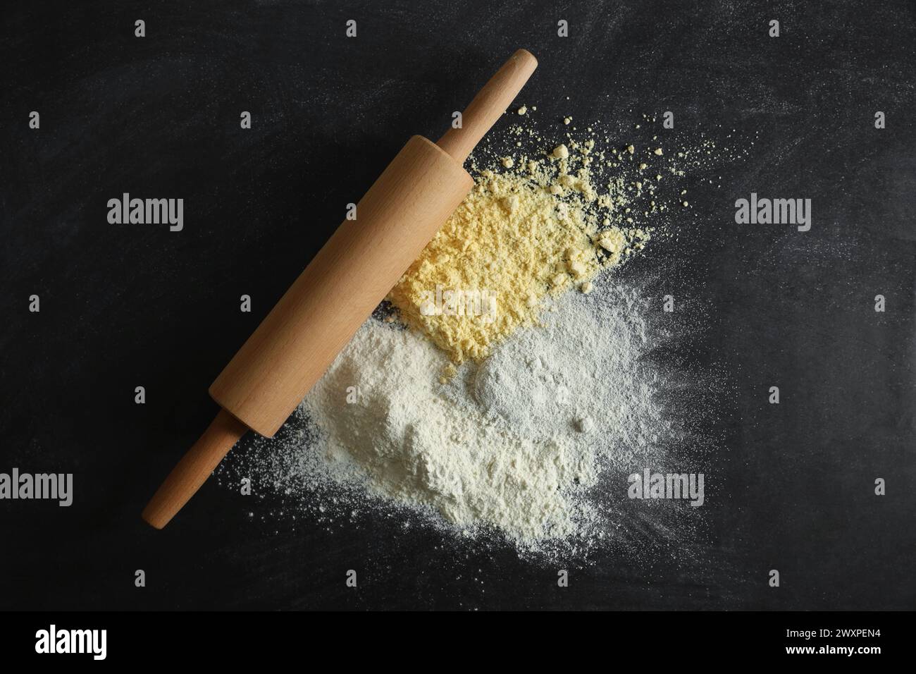 Rolling pin and different types of flour on black table, top view Stock ...