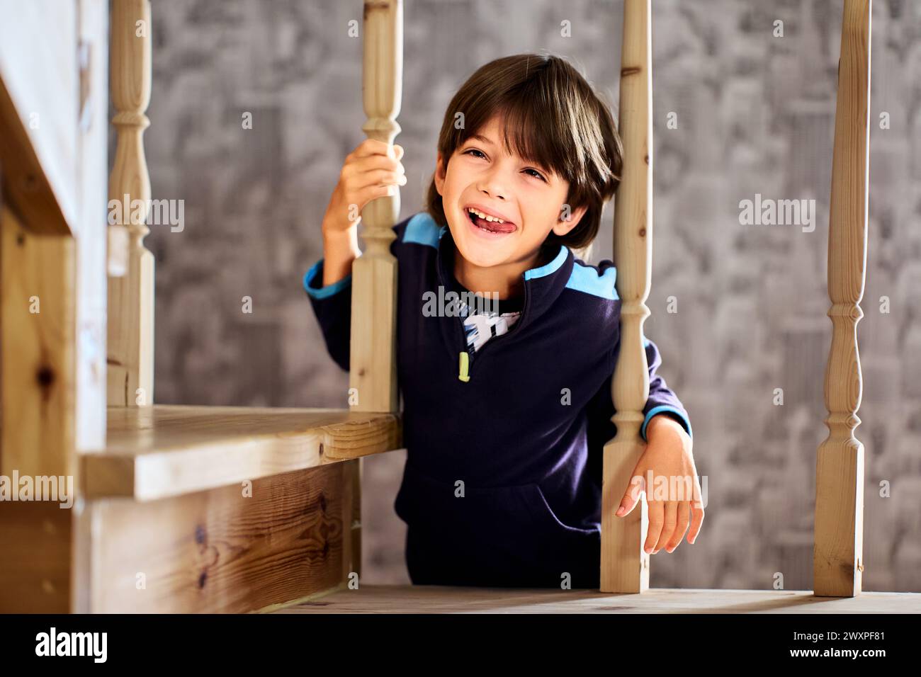 Seven year old boy stuck out his tongue while making faces on wooden ...