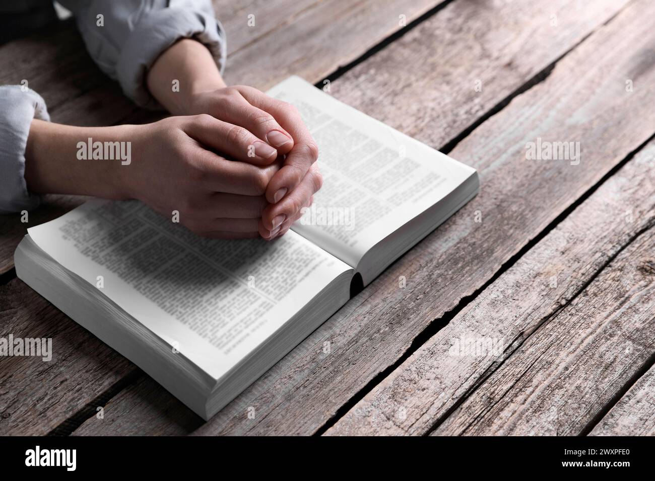 Religion. Christian woman praying over Bible at wooden table, closeup ...