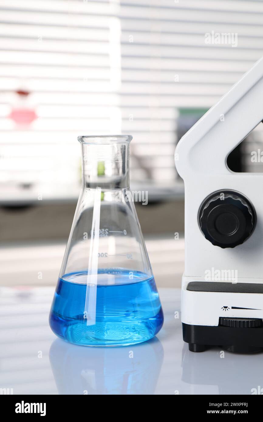 Laboratory analysis. Flask with blue liquid and microscope on white ...
