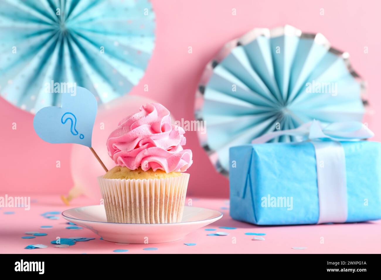 Delicious cupcake with question mark, gift box and decorations on pink ...