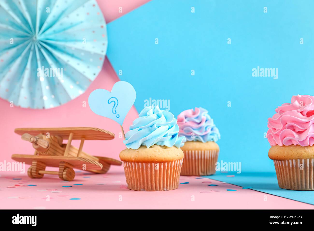 Delicious cupcakes with question mark, wooden plane and decor on color ...