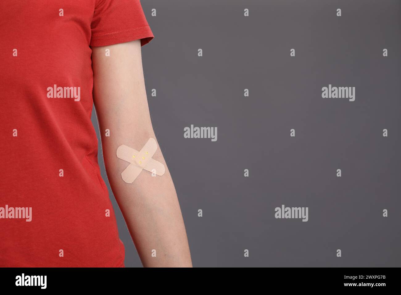 Blood donation. Woman with sticking plaster on her arm against grey ...