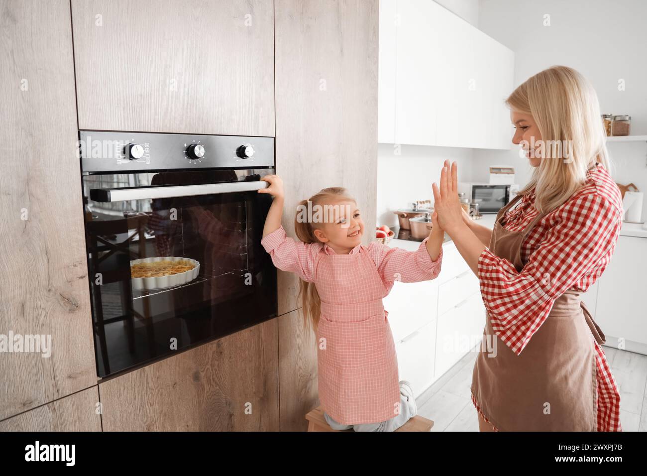 Little girl with her mother giving each other high-five while baking ...