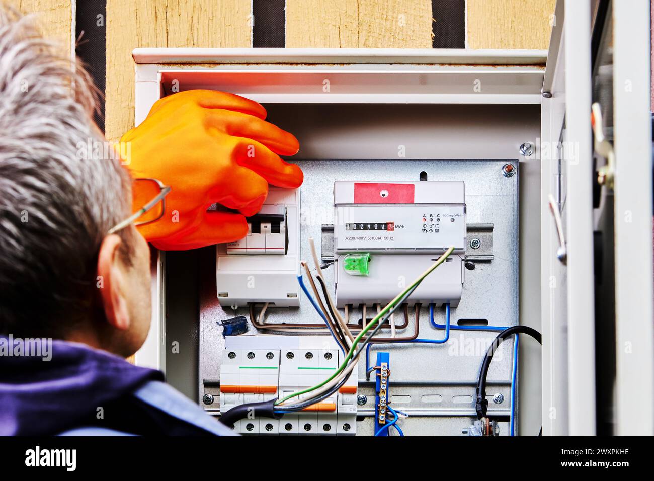 An electrician wearing protective dielectric gloves turns off power ...
