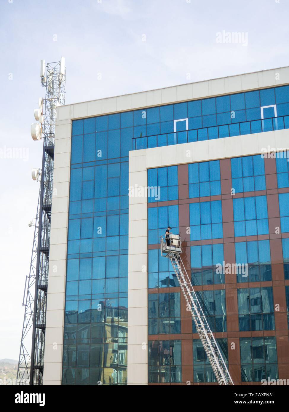 Cleaning windows in a large glass building. Work at height on a lift ...