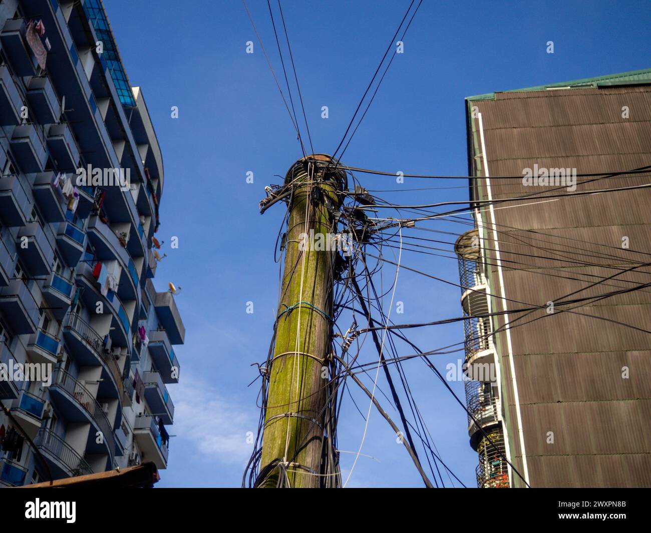 Many wires are piled on a wooden pole in a modern city. Electrification ...