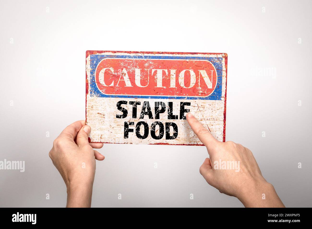 Staple Food. Metal warning sign in a woman's hand on a white background ...