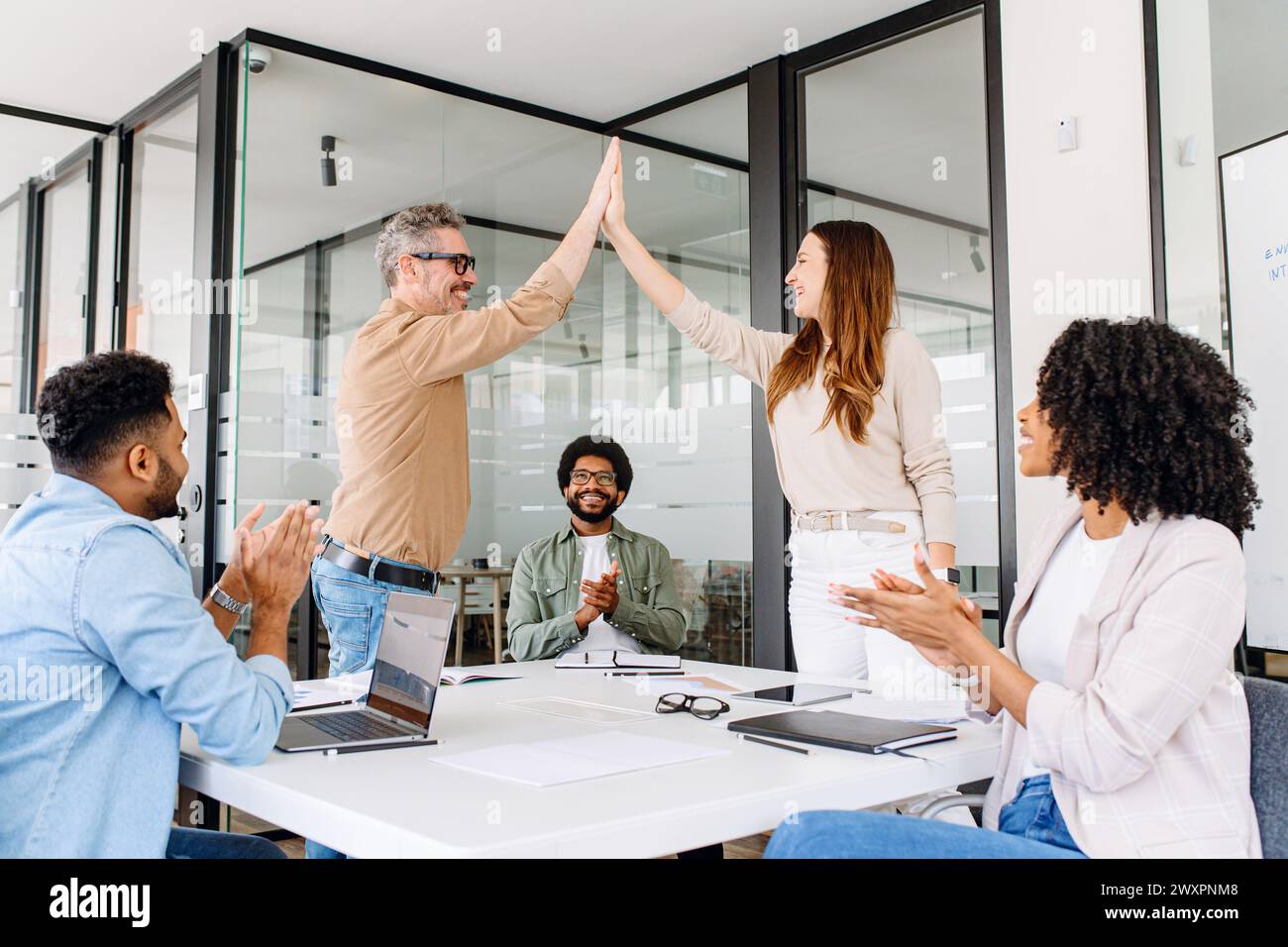 In a spirited office atmosphere, colleagues share a high-five ...