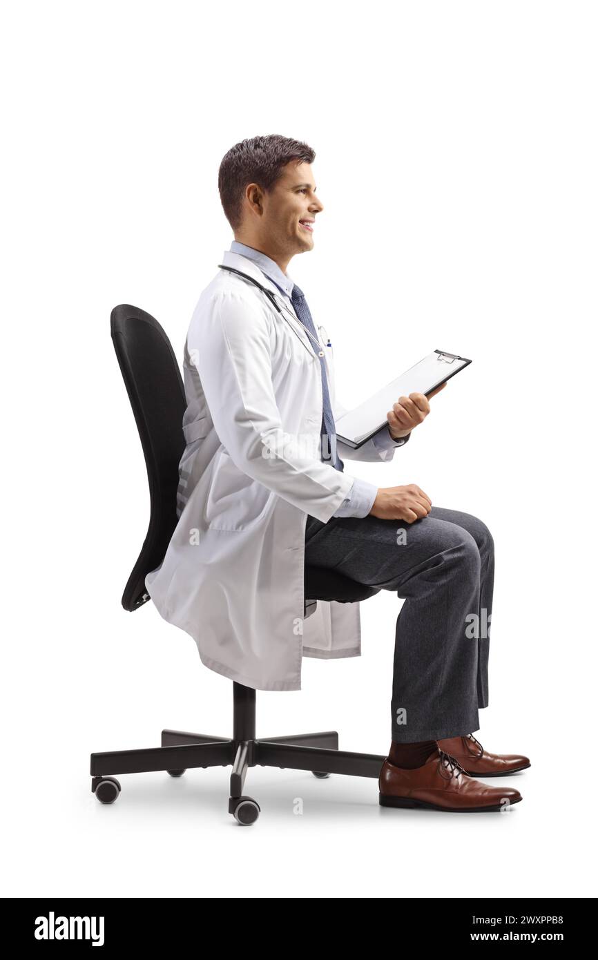 Smiling male doctor sitting in an office chair and holding a clipboard ...