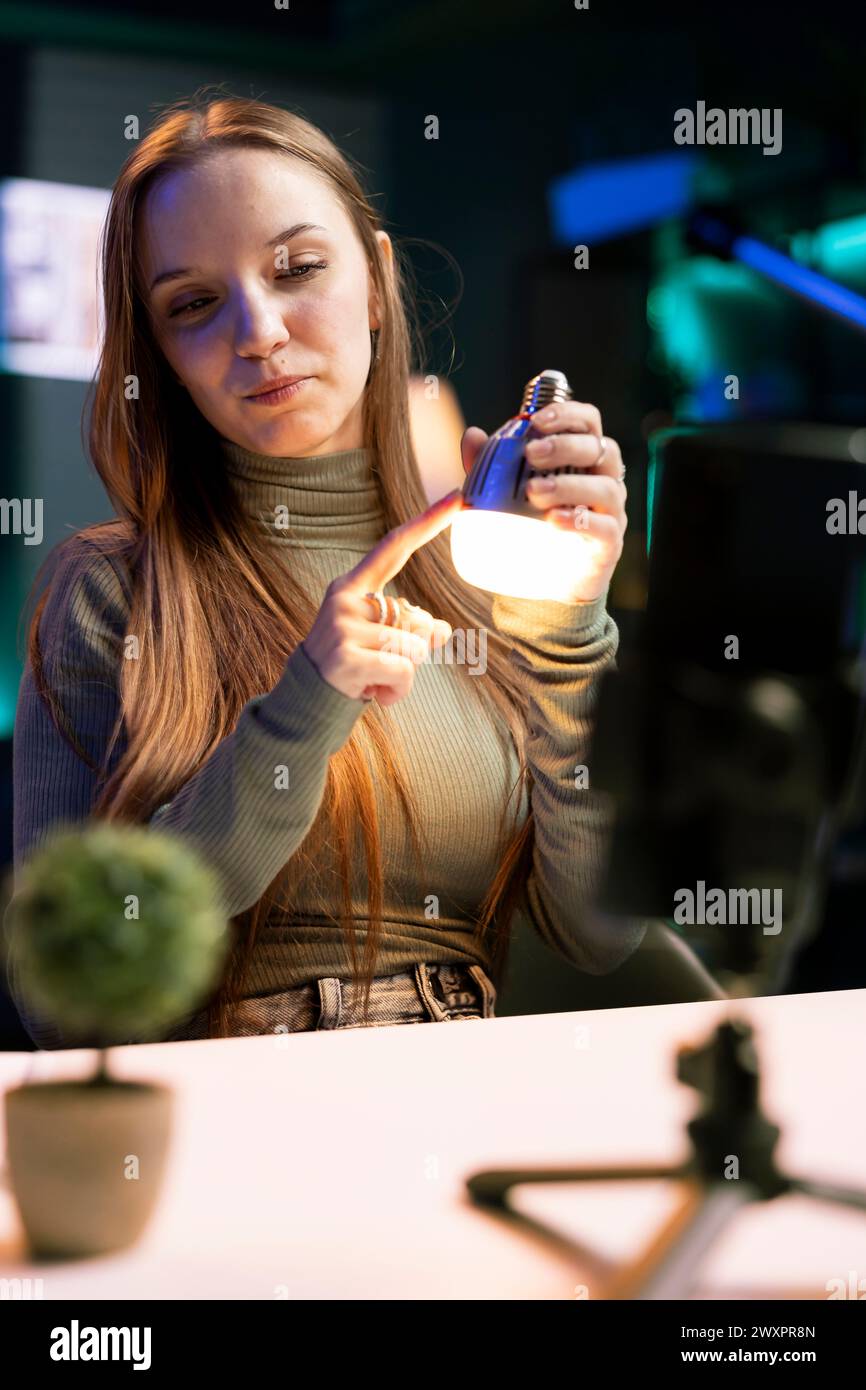 Influencer in neon lit studio filming review of light bulb using ...