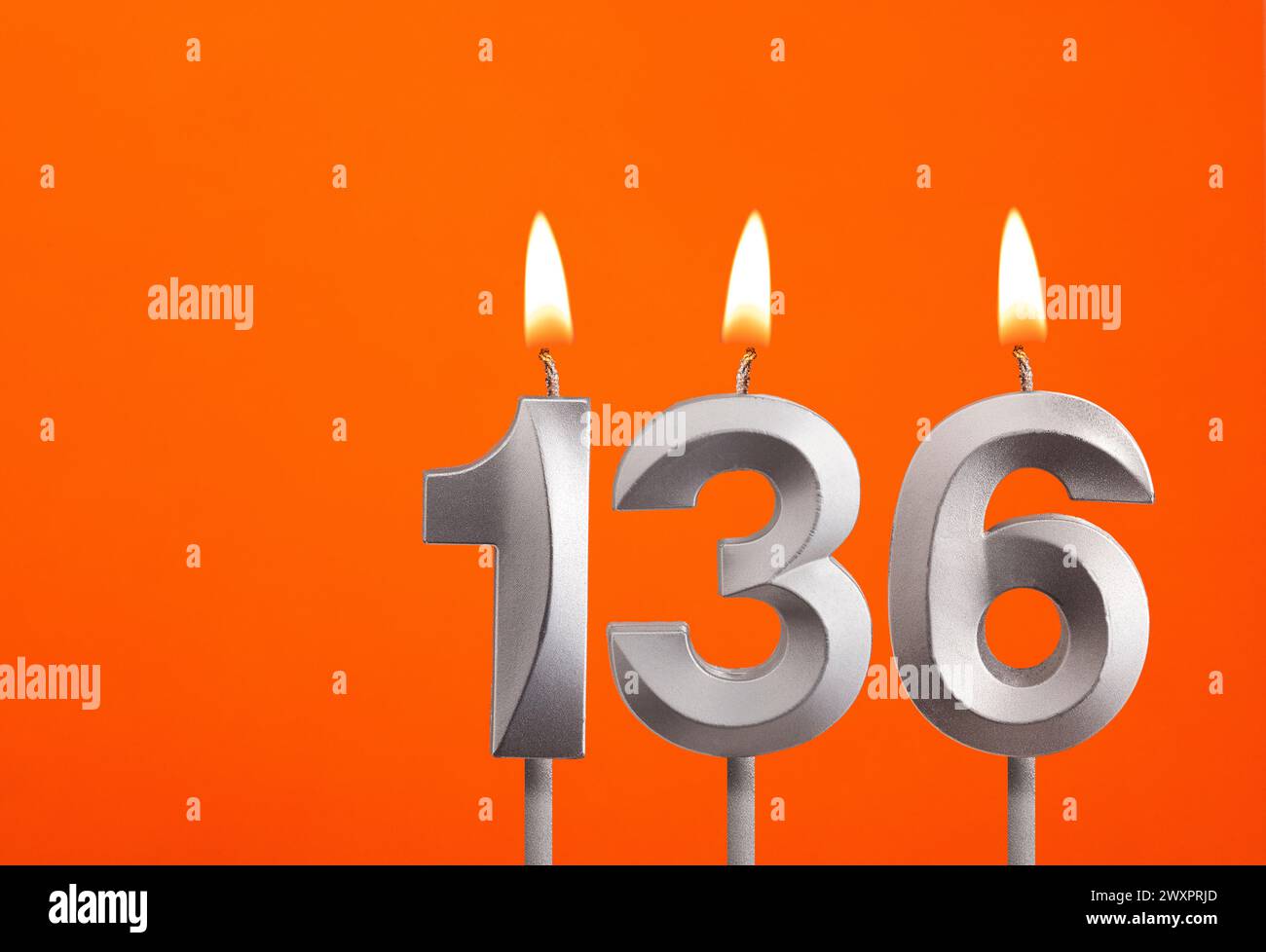 Candle number 136 - Birthday in orange background Stock Photo - Alamy