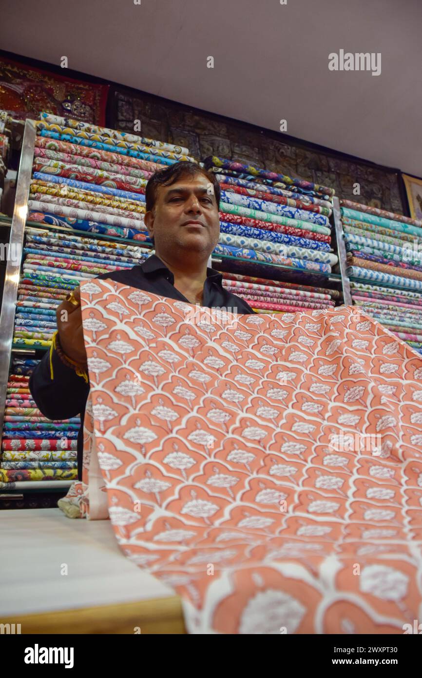 Indian seller showing textiles with variety of colors in shop of a ...
