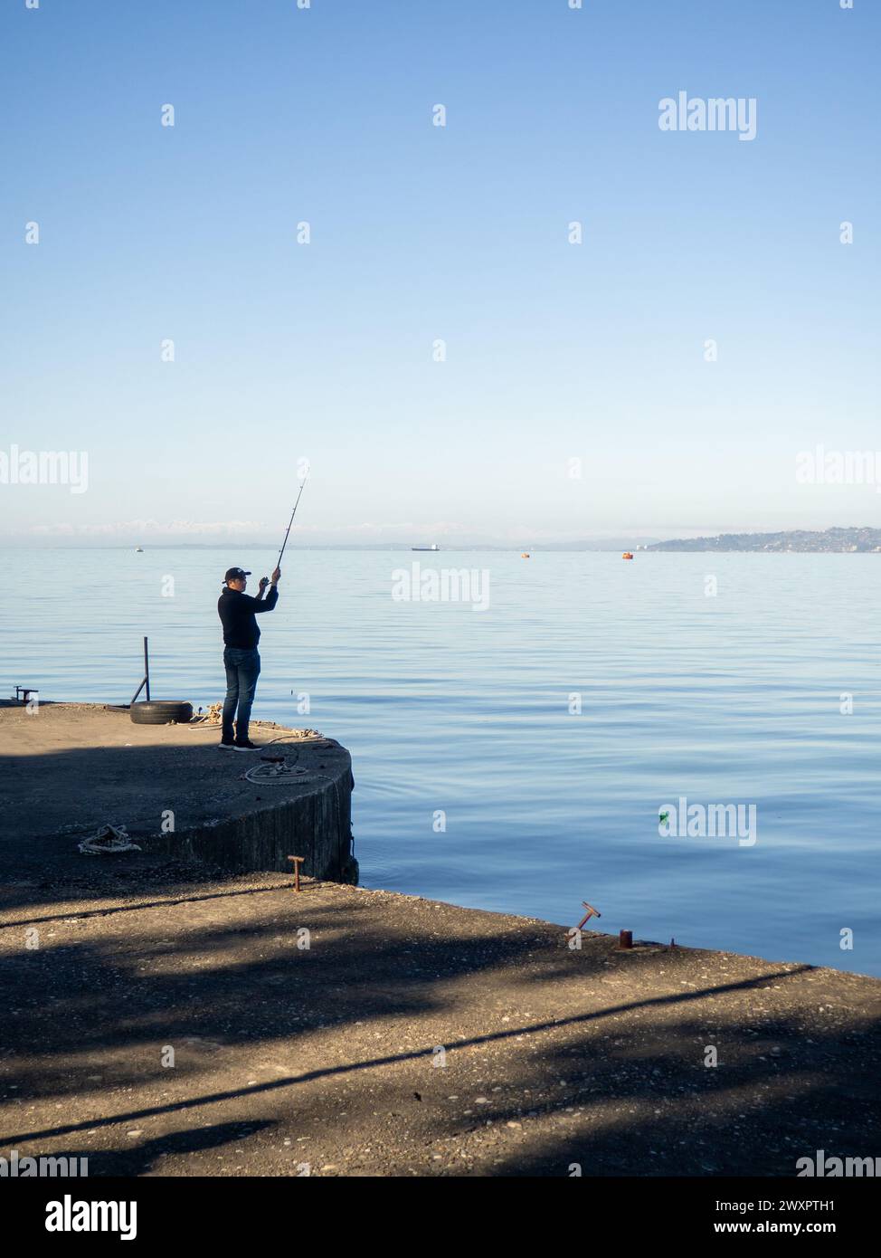 Batumi, Georgia. 02.31.2024 Fisherman with a fishing rod on the pier ...