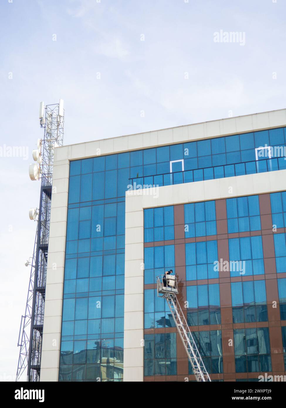 Cleaning windows in a large glass building. Work at height on a lift ...