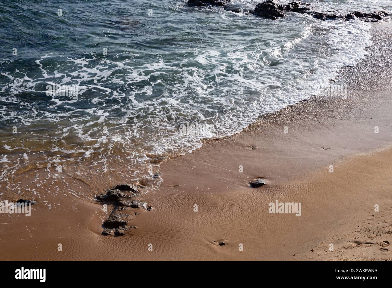 Seaside of a beach with small foaming waves. Sunny day, calm sea water ...