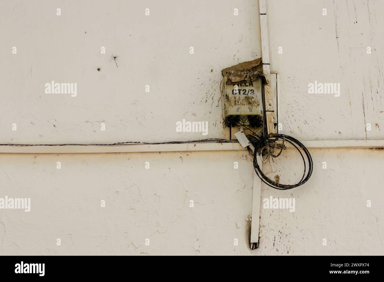 A rusty, weathered and neglected cable connection box in a dirty white ...