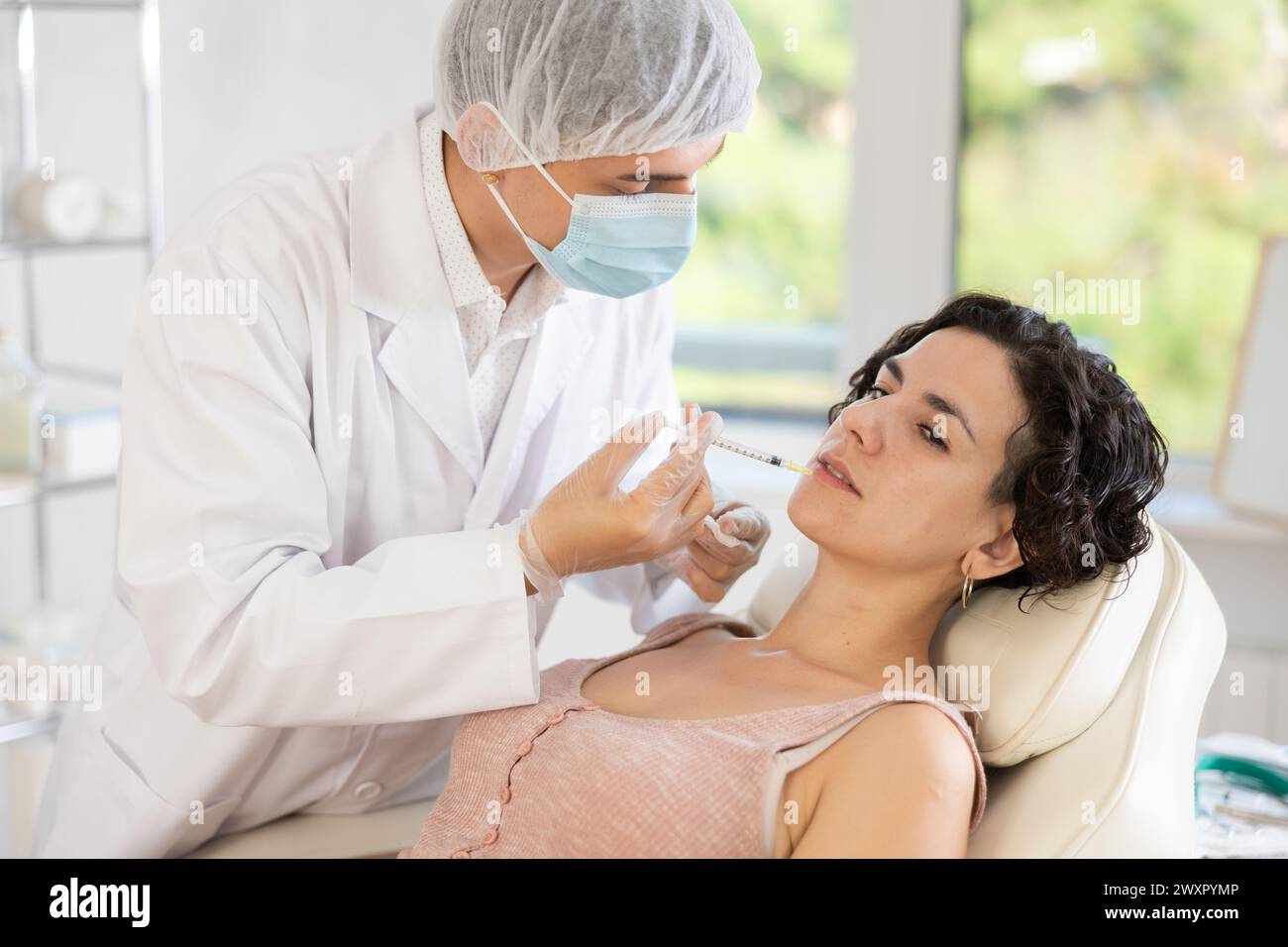 Middle-aged woman having face care by means of injection in aesthetic ...