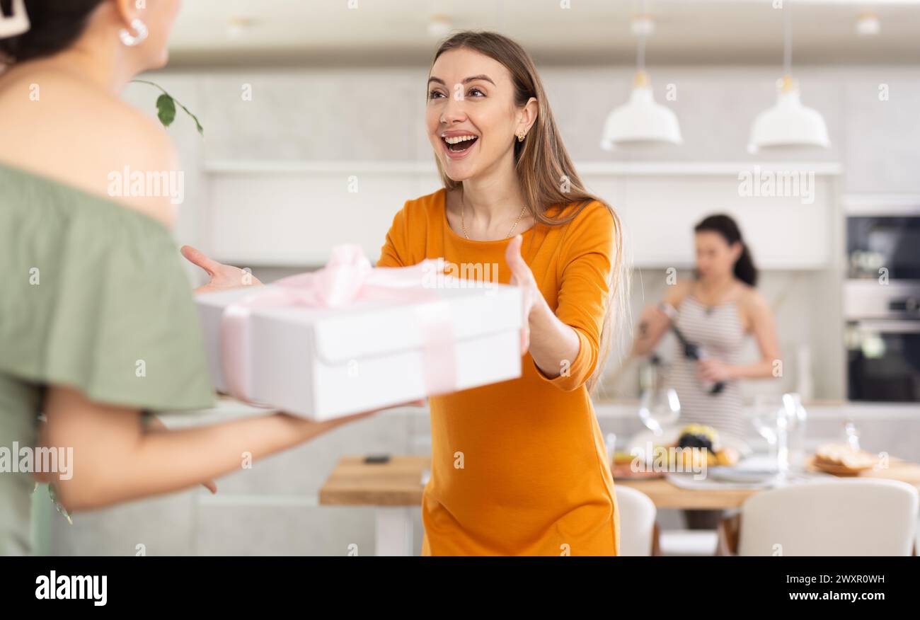 Group of women greeting each other and giving gift Stock Photo - Alamy