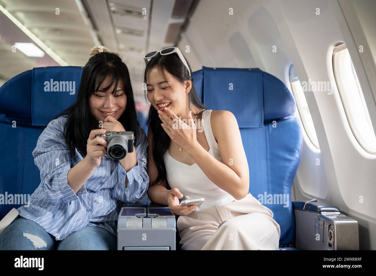 Two cheerful young Asian female friends are enjoying talking and taking ...