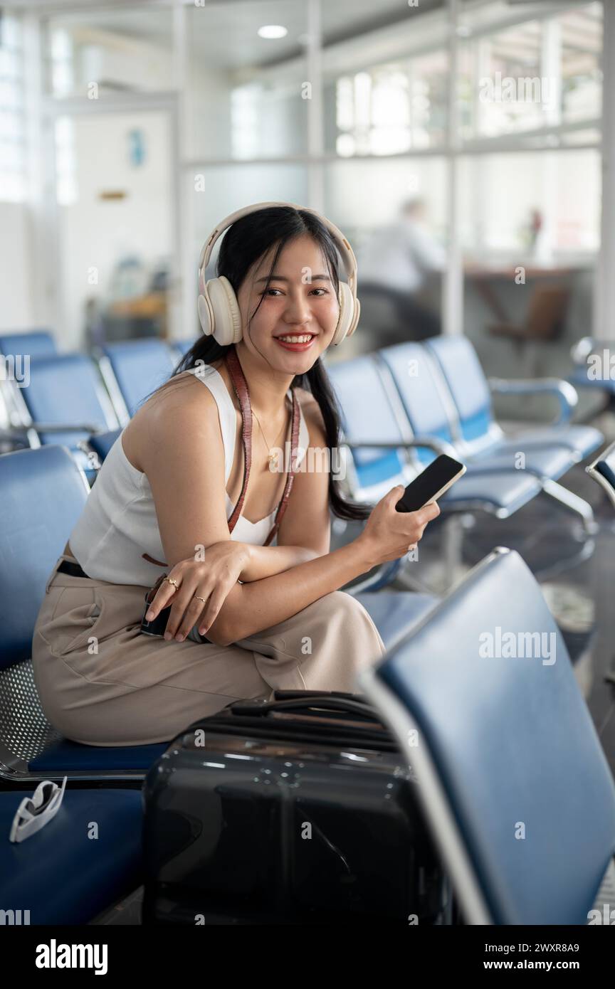 A beautiful Asian female passenger is listening to music on her ...