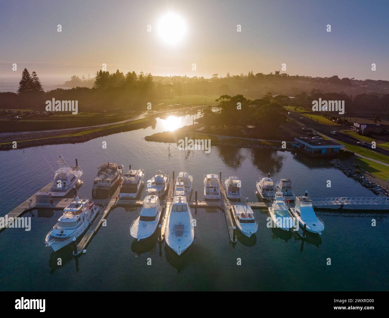 Aerial view of a foggy sunrise over a coastal marine full of boats at ...