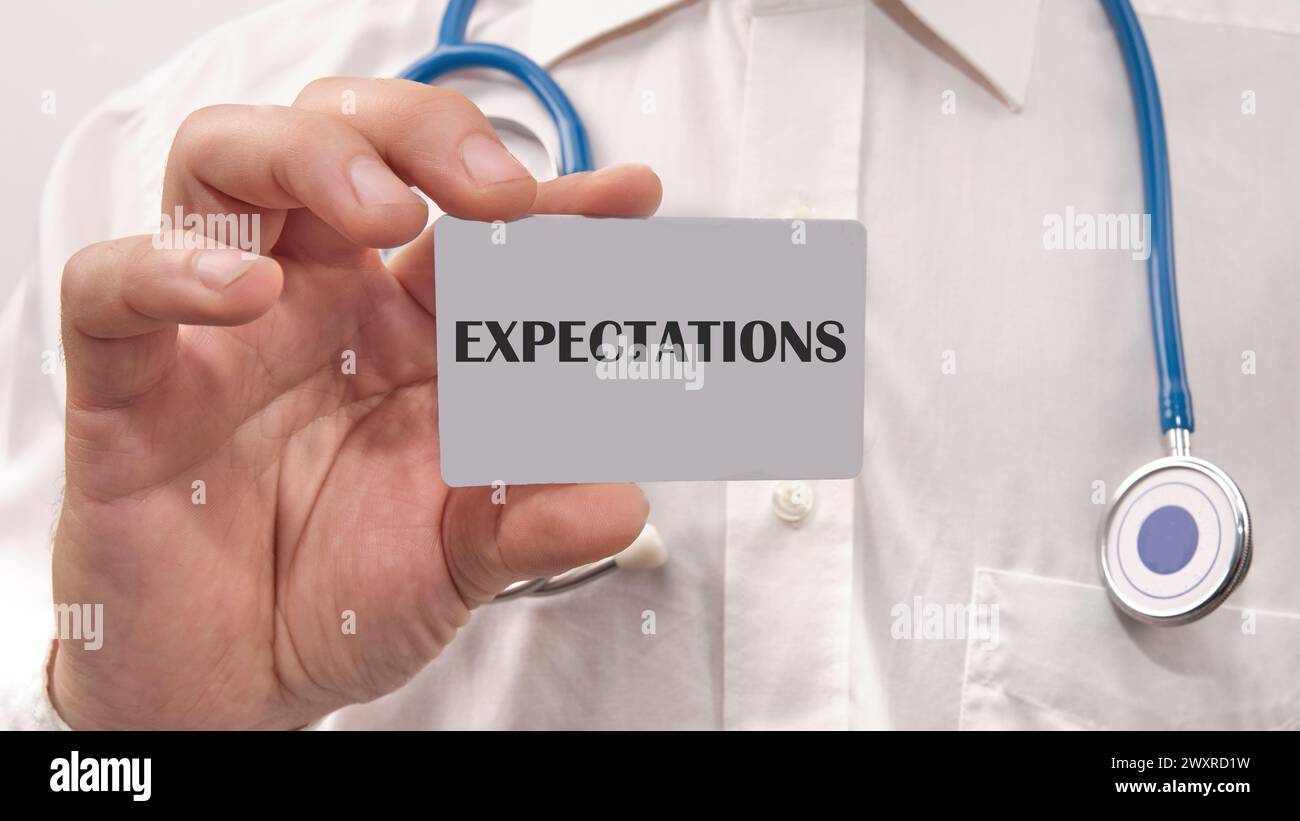 Word Expectations written on the card in the hand of a man in a white ...