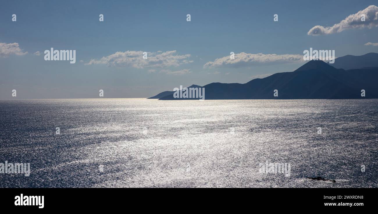 Silver water against blue cloudy sky background. Mountain silhouette ...