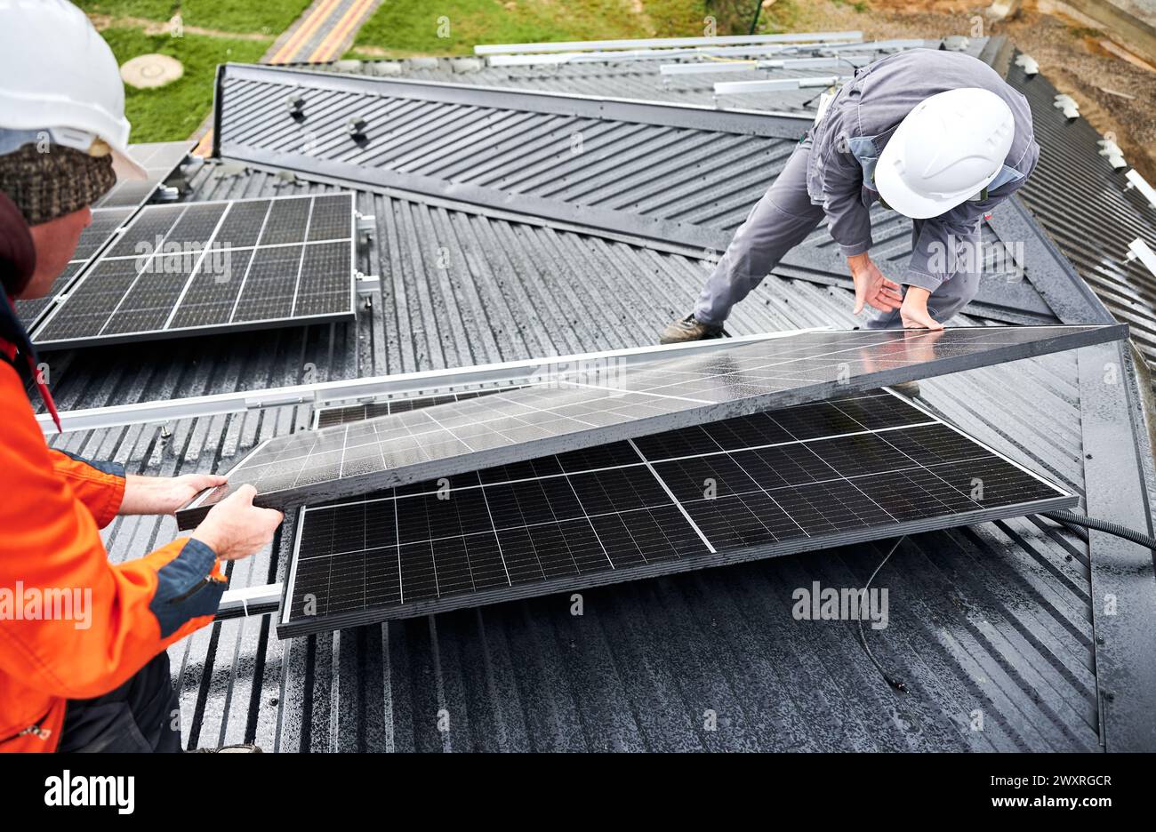 Workers building solar panel system on roof of house. Men technicians ...