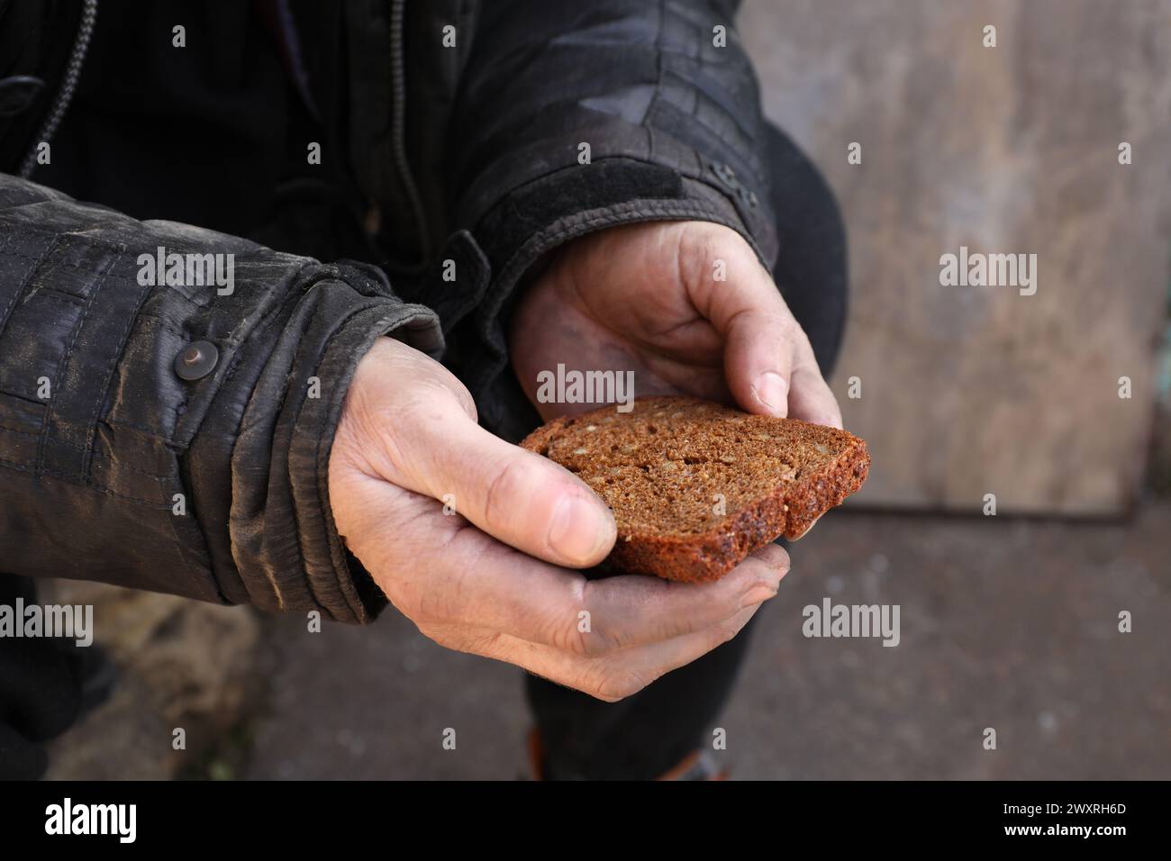 Poor homeless man holding piece of bread outdoors, closeup Stock Photo ...