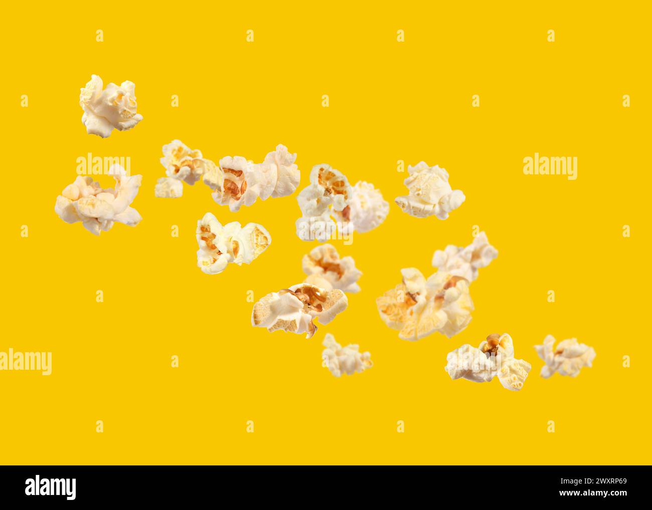 Tasty fresh popcorn flying on yellow background Stock Photo - Alamy