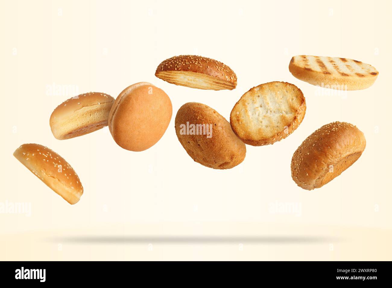 Fresh burger buns falling on beige background Stock Photo - Alamy