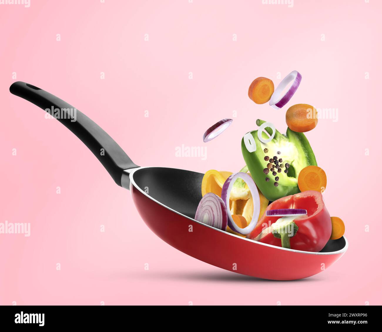Frying pan with fresh ingredients in air on pink background Stock Photo ...