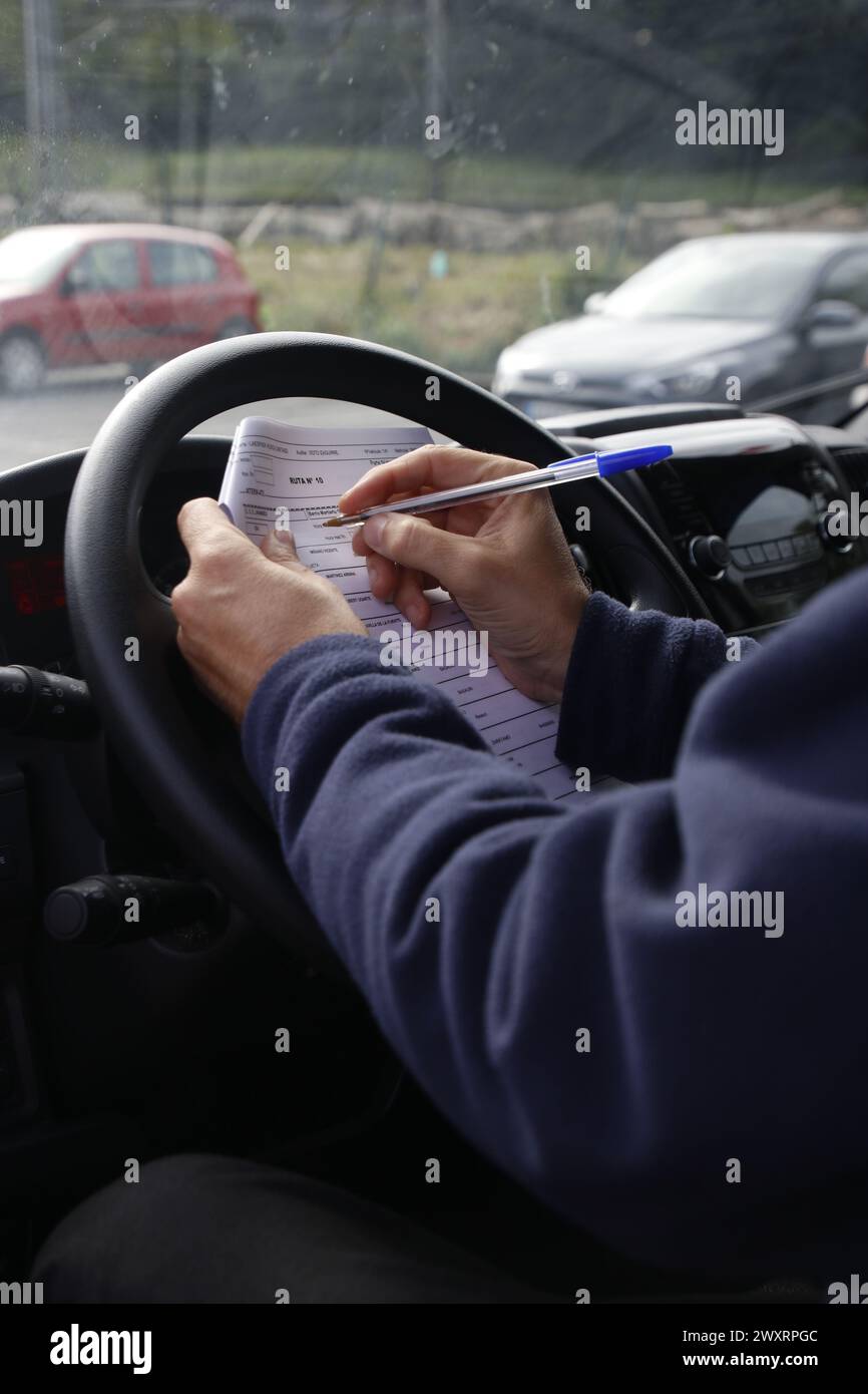 A man multitasking, holding a clipboard and reading papers while ...