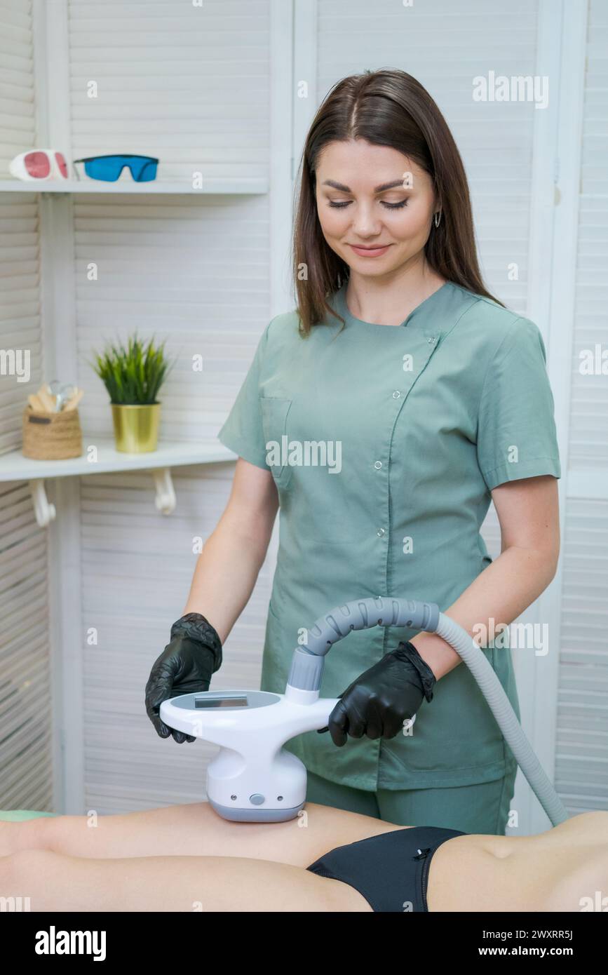 woman is getting a laser treatment on her leg. She is wearing a green ...