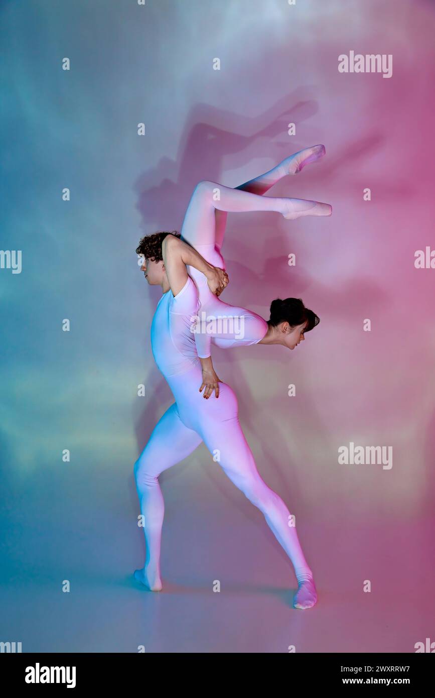 Ballet dancers in back-to-back lift, with male in supportive stance ...