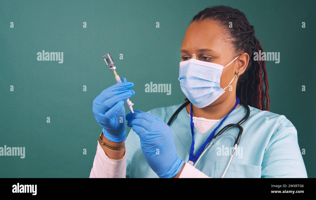 Black female doctor draws up injection, vaccine vial, needle, IVF ...