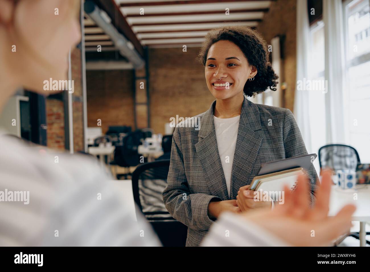 Two female managers met in the office interior and stopped to talking ...