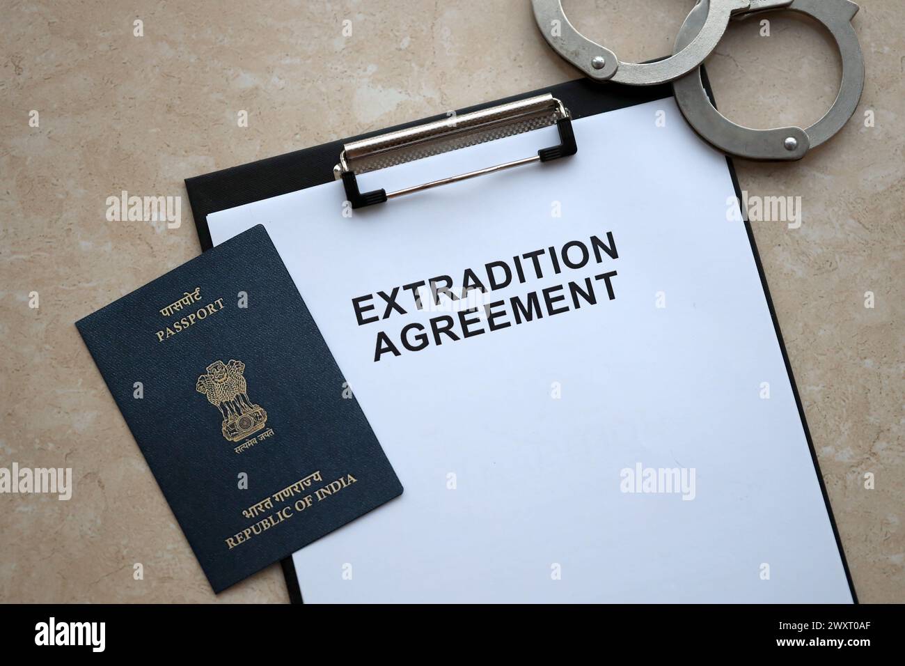 Passport of India and Extradition Agreement with handcuffs on table ...