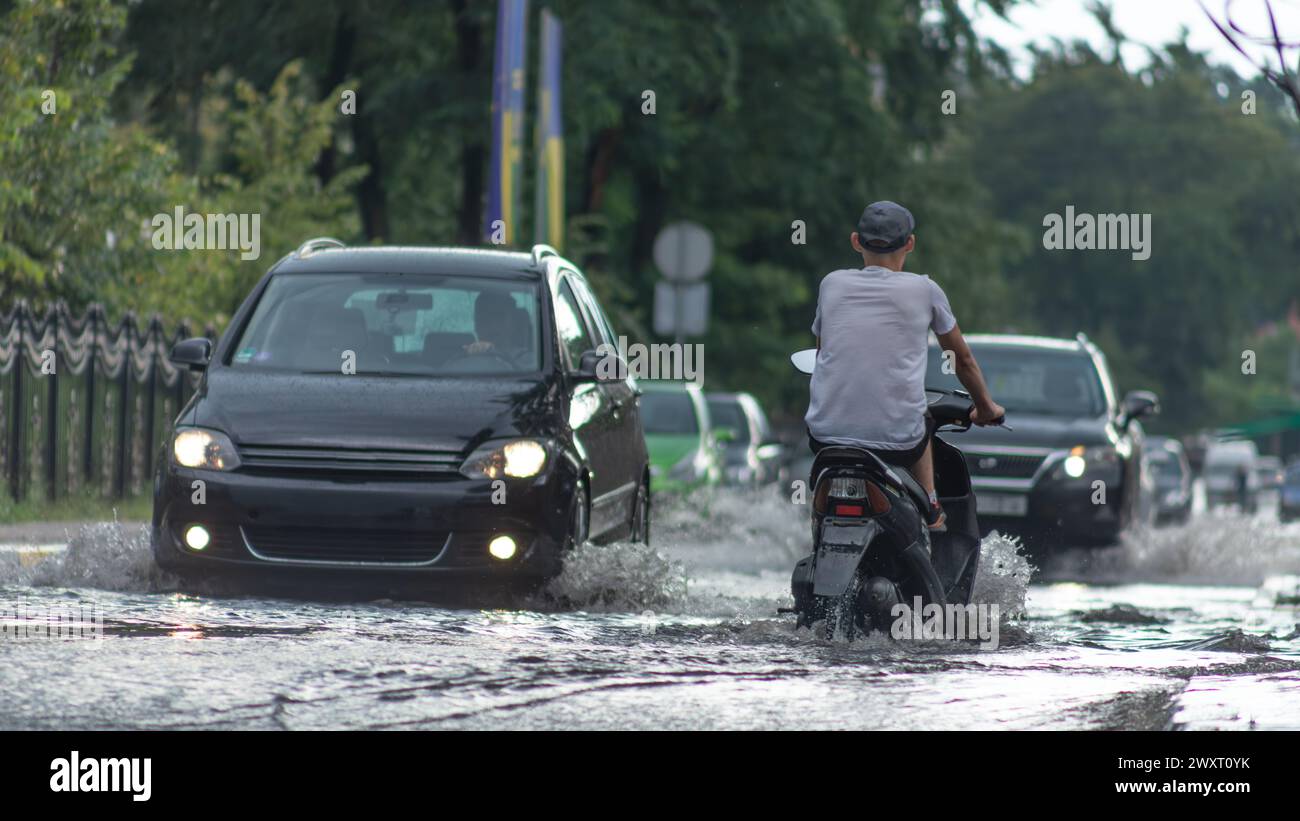 Wet Commute: Moped Navigating Rain and Flooded Streets Stock Photo - Alamy